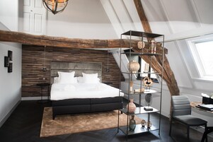 Quarto moderno com uma cama grande, cabeceira de madeira, estante de vidro e uma escrivaninha com cadeira.