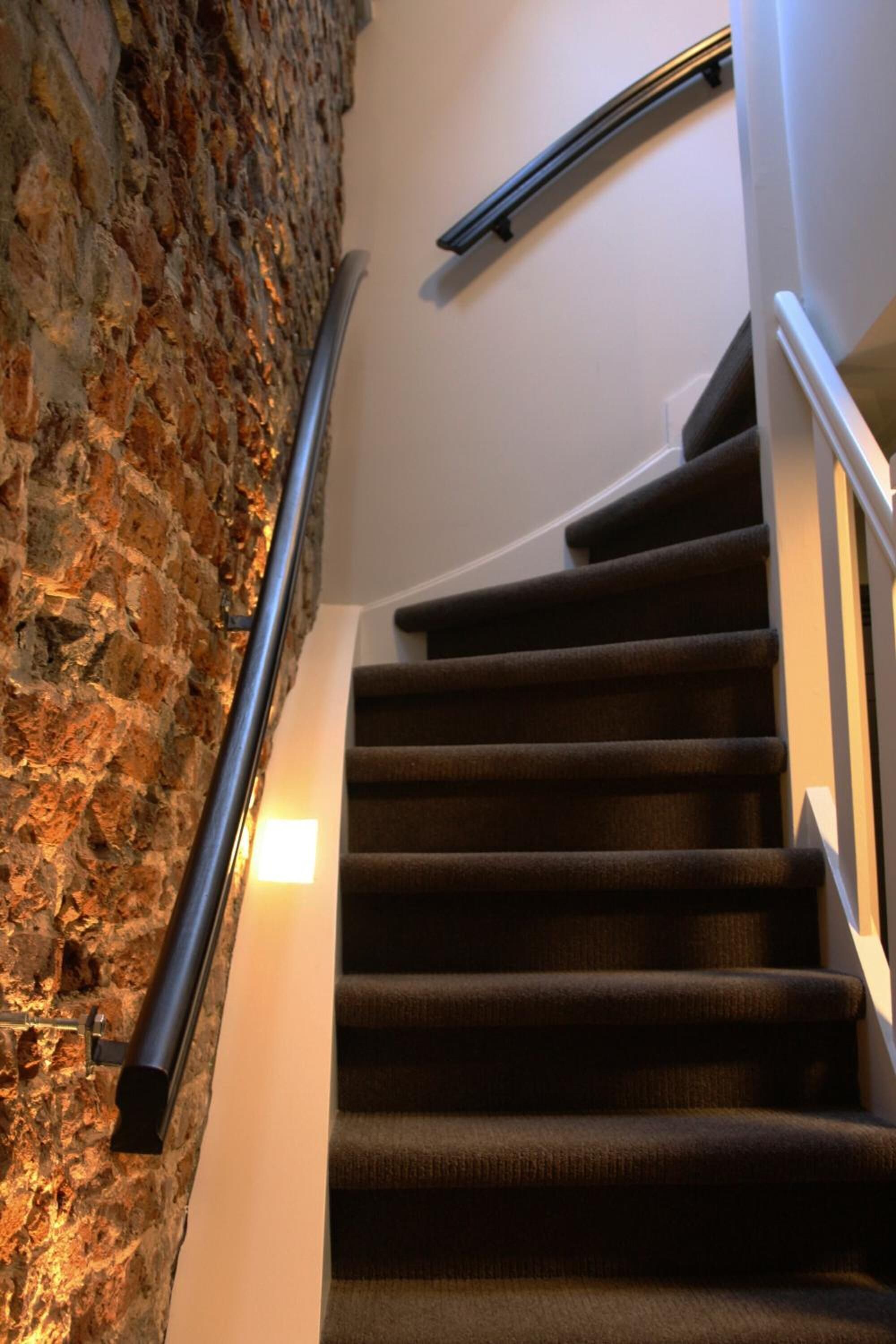 Uma escadaria com uma parede de pedra de um lado e um corrimão do outro.