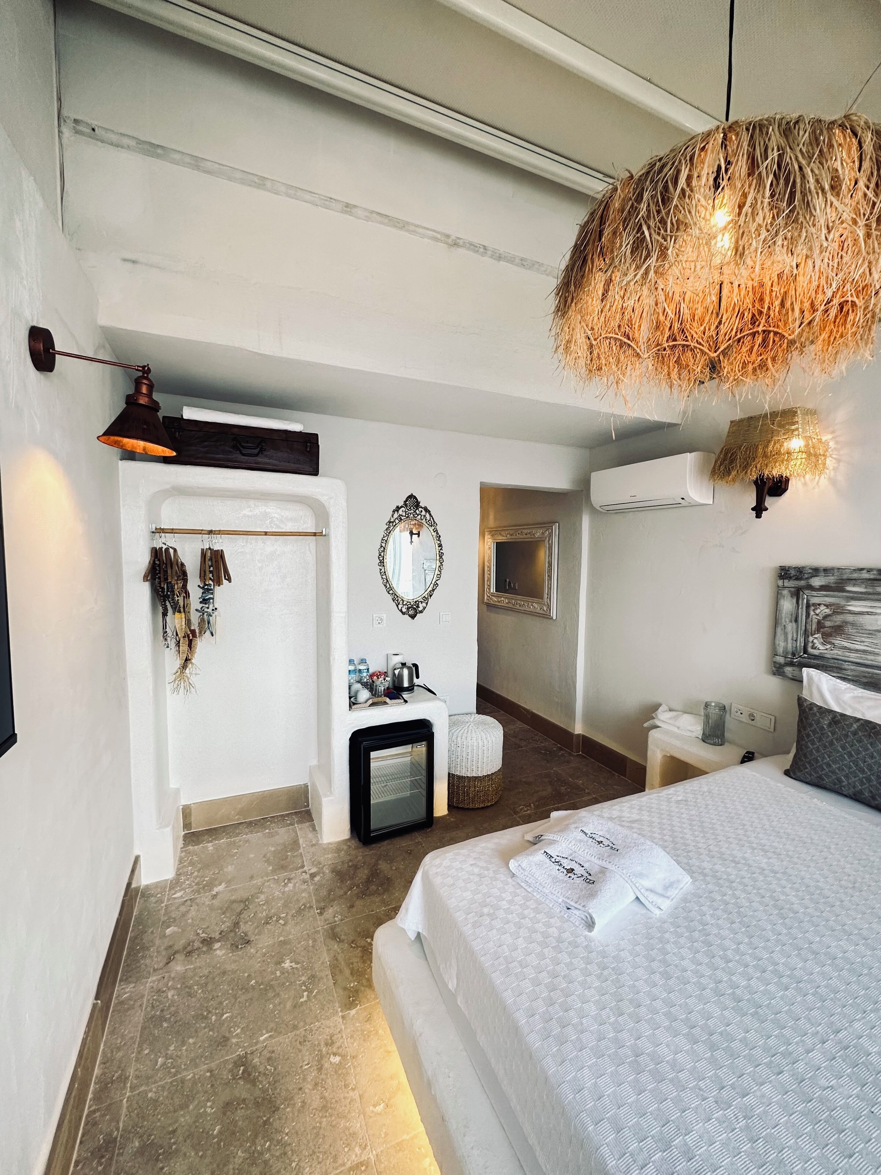 Quarto moderno com cama grande, um espaço de estar pequeno, um espelho e uma kitchenette.