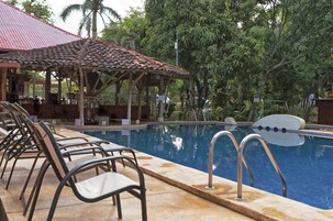 Uma área de piscina com espreguiçadeiras e um espaço de estar coberto.