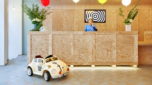 Balcão de atendimento com acabamento em madeira, um recepcionista e um carrinho de brinquedo.