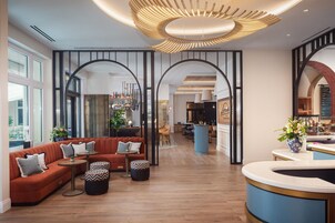 Um saguão moderno de hotel com um sofá vermelho, área de bar e vista para a cozinha.