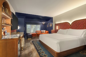 Quarto de hotel com cama, escrivaninha, sofá e vista para o exterior.