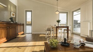 Cozinha espaçosa com armários de madeira, área de jantar com mesa e cadeiras, e vista para a água.