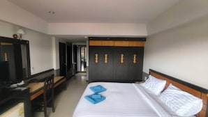 Quarto de hotel com uma cama grande, uma escrivaninha, um espelho e um guarda-roupa.