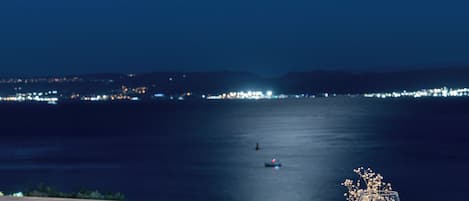 Mesa posta para o jantar com vista para o mar e paisagem urbana ao fundo.
