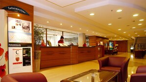 Um saguão de hotel com balcão de recepção, área de estar e escadaria.
