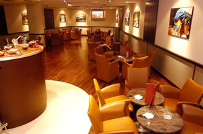 Um restaurante espaçoso com várias áreas de estar, incluindo mesas redondas e cadeiras com encosto alto.