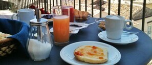 Uma mesa com itens de café da manhã, incluindo torradas, um copo de suco de laranja e uma caneca.