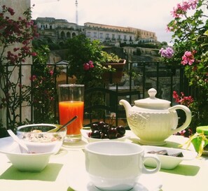 Mesa posta para o pequeno-almoço, com tigela de cereais, copo de sumo de laranja, bule e chávena.