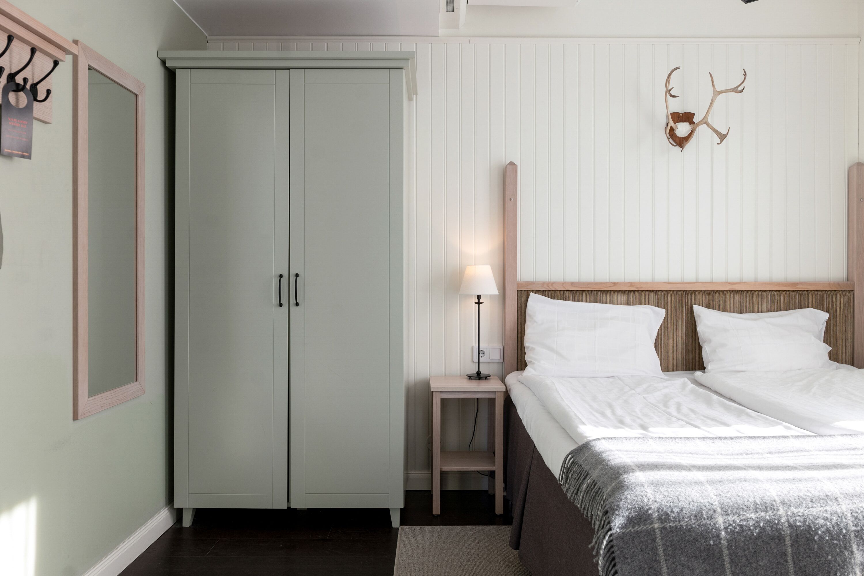 Quarto com cama, mesa de cabeceira, abajur e guarda-roupa.