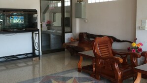Uma sala de estar ampla com uma janela grande, um sofá de madeira, uma mesa de jantar e um piso decorado com padrão de estrelas.