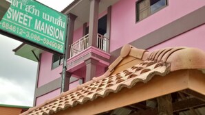 Um edifício rosa com uma placa que diz 'SWEET MANSION' e um número de contato.