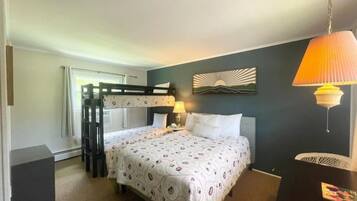 Quarto com uma cama beliche, uma mesa de cabeceira com abajur e uma obra de arte pendurada na parede.