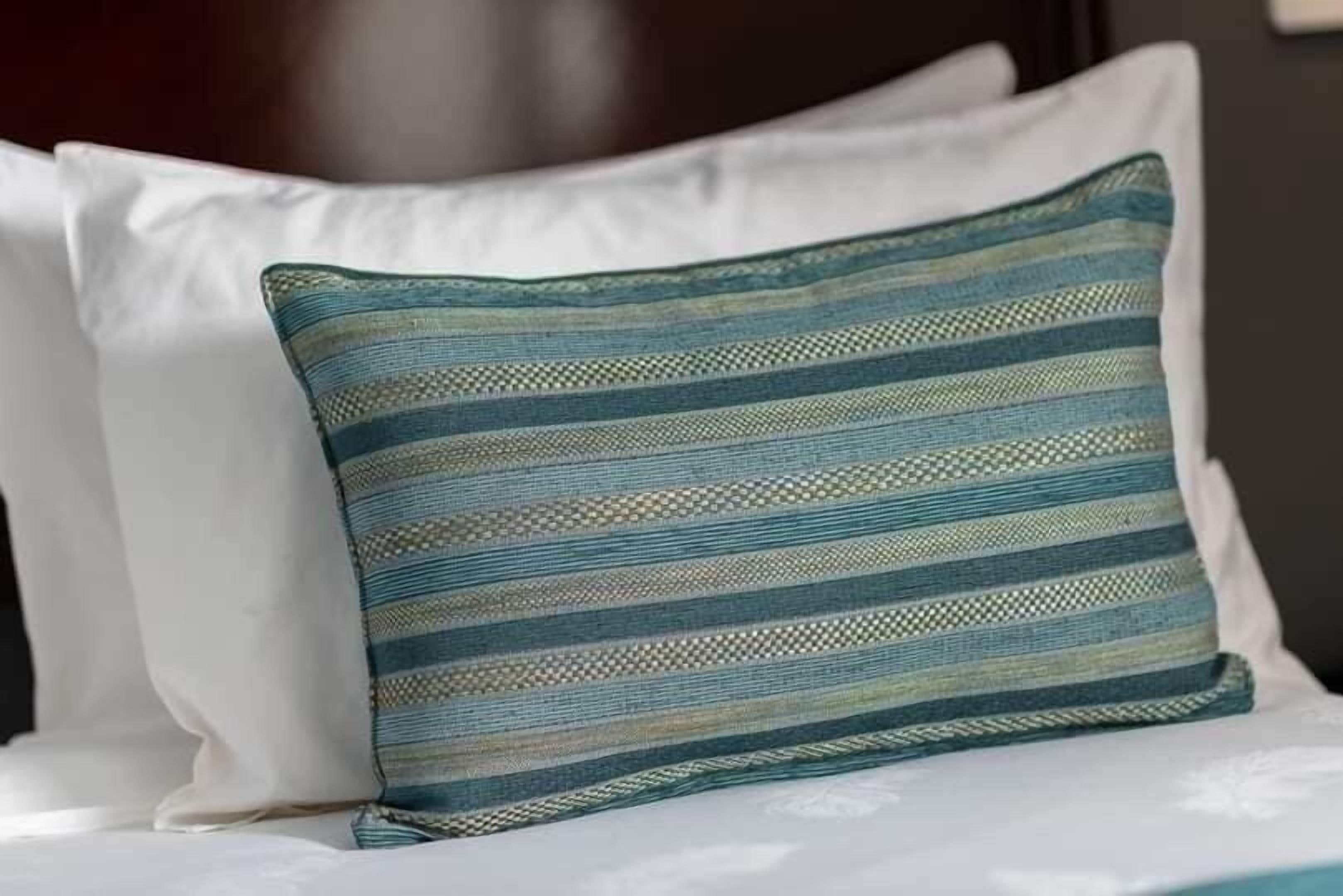 Um travesseiro com padrão listrado sobre uma cama.