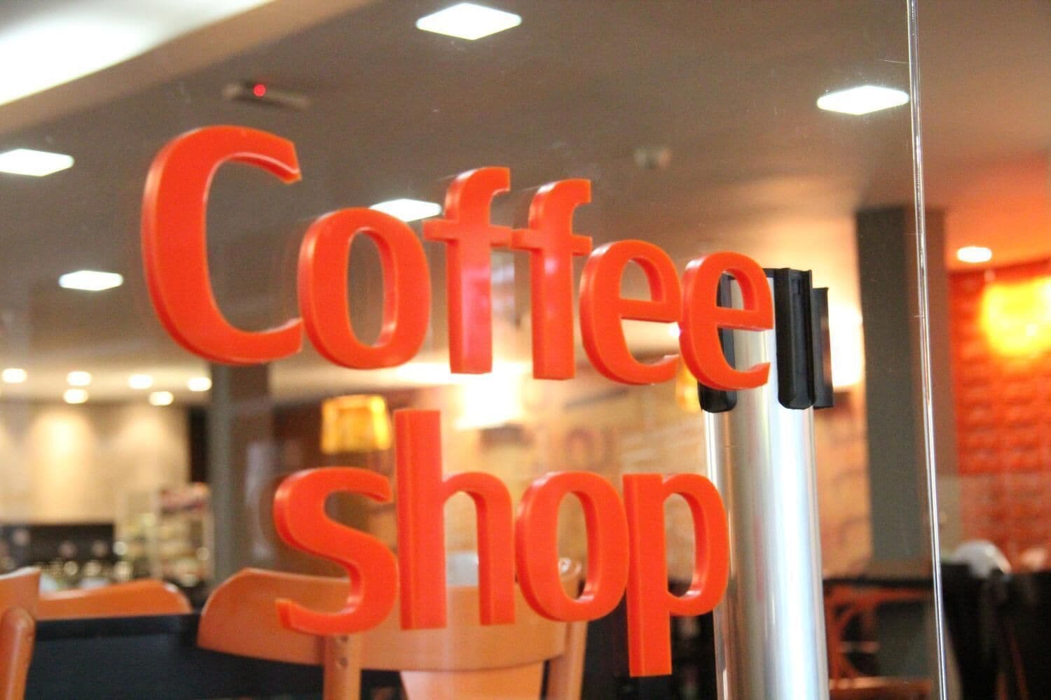 Uma janela de vidro com a inscrição "Coffee Shop" em letras vermelhas.