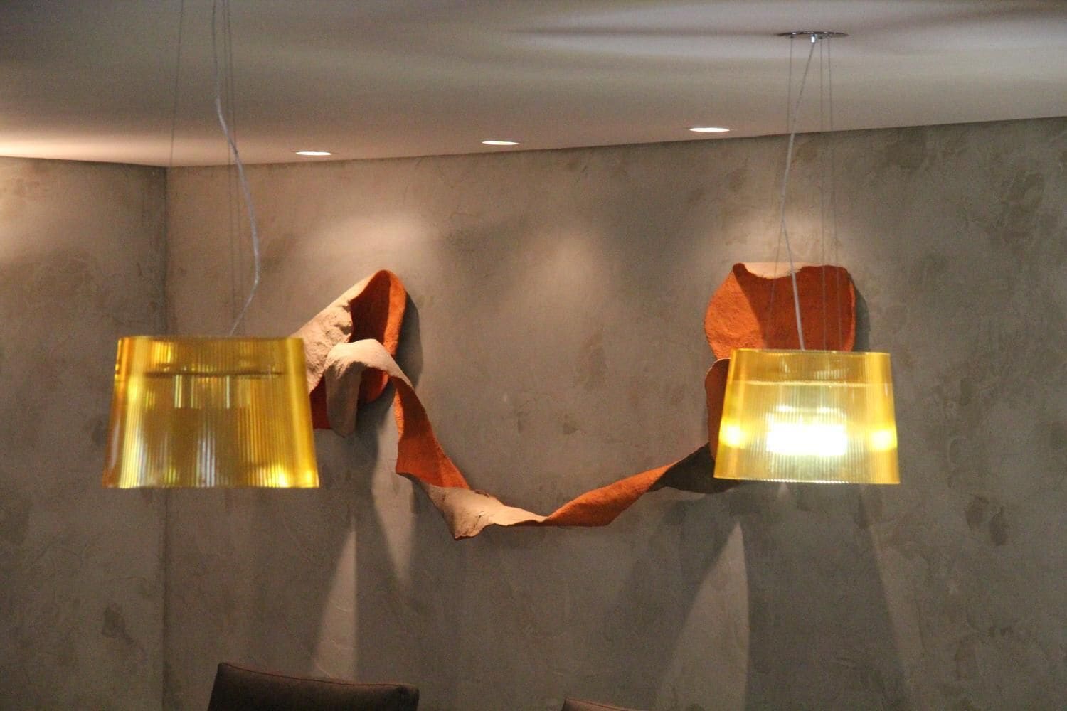 Quarto com design moderno, destacando uma luminária singular e uma parede texturizada.
