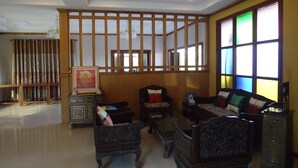 Uma sala de estar em estilo tradicional, com mobiliário de madeira e um biombro decorativo.