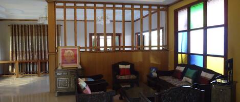 Uma sala de estar em estilo tradicional, com mobiliário de madeira e um biombro decorativo.