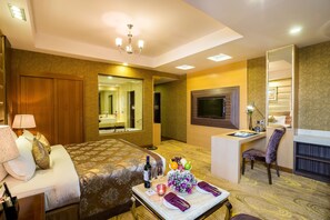 Quarto de hotel com cama, escrivaninha e área de estar.