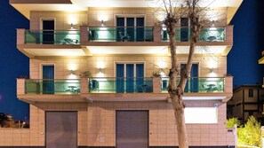 Um edifício residencial de vários andares com varandas, cada uma delas com guarda-corpos de vidro e área para sentar ao ar livre.