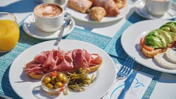 Uma mesa de café da manhã com pratos de comida, uma xícara de café e um copo de suco de laranja.