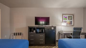 Quarto de hotel com duas camas, televisão, escrivaninha, cadeira, micro-ondas e frigorífico.
