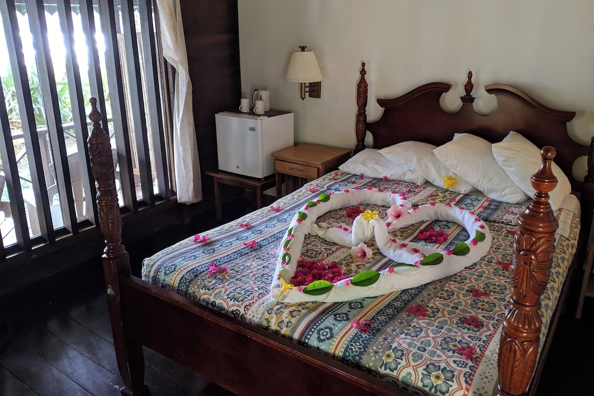 Cama arrumada com um arranjo floral e um edredom estampado.