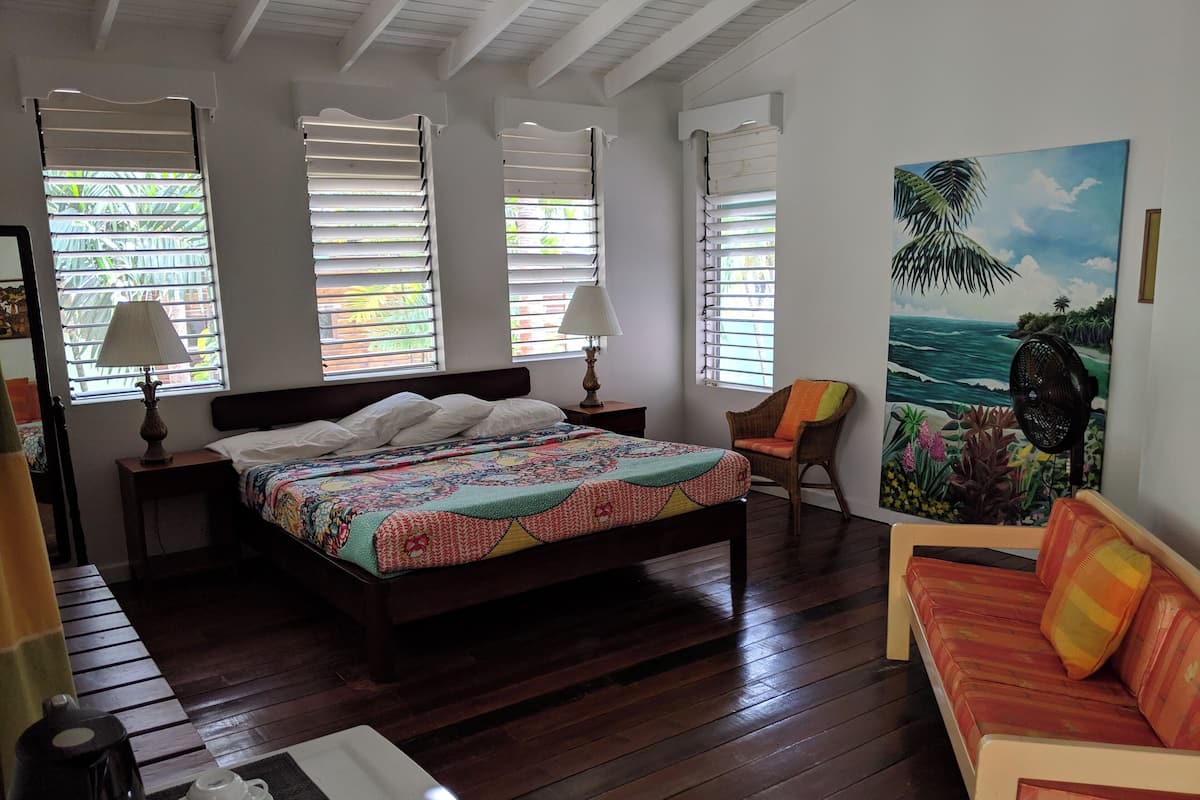 Quarto com cama, poltrona, sofá e um quadro na parede.