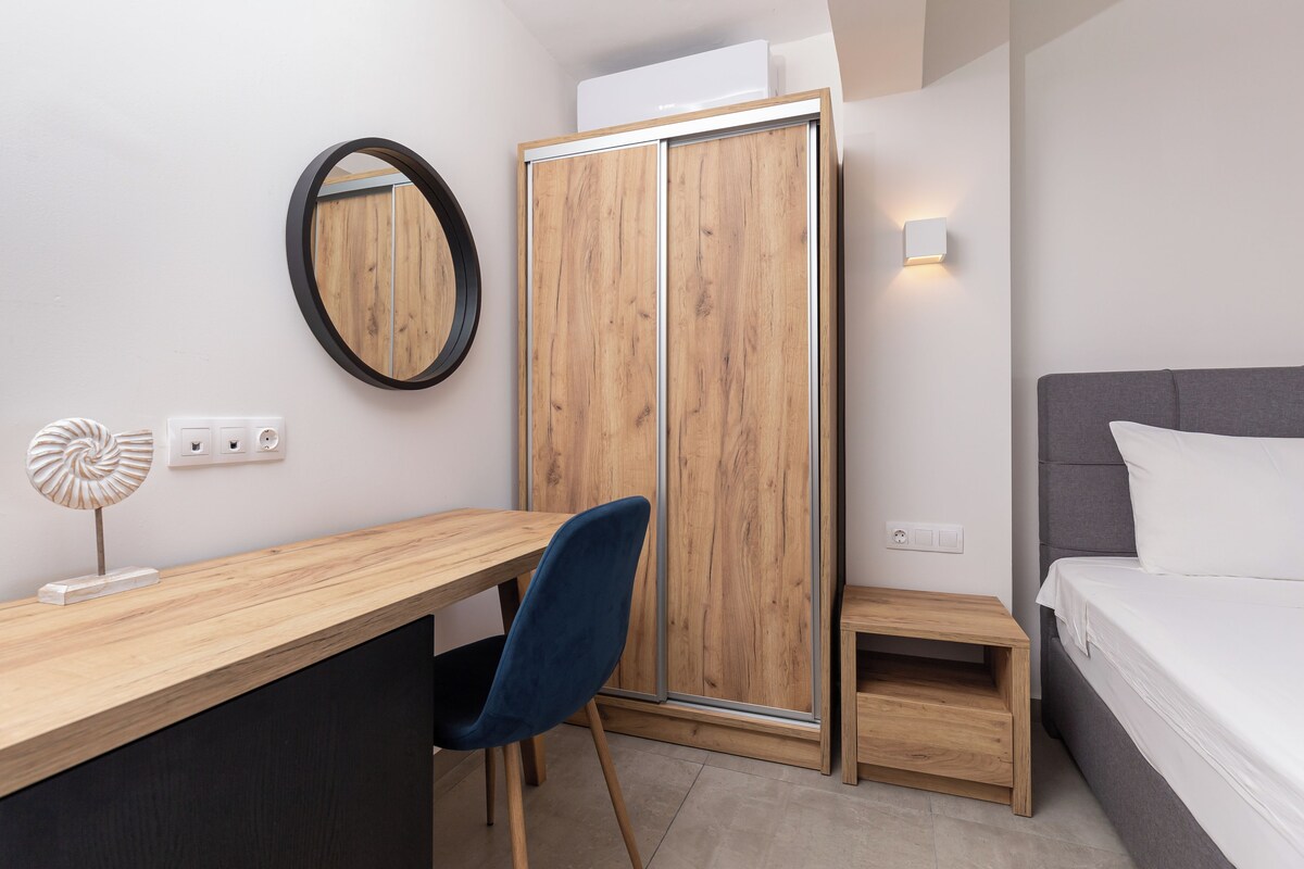 Quarto com cama, escrivaninha, cadeira, guarda-roupa e mesa de cabeceira.