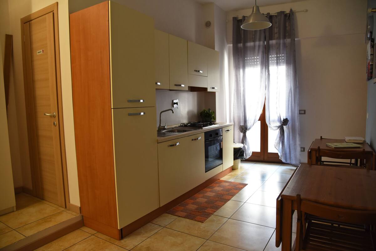 Uma cozinha compacta com área de refeições, armários de madeira, fogão e mesa.