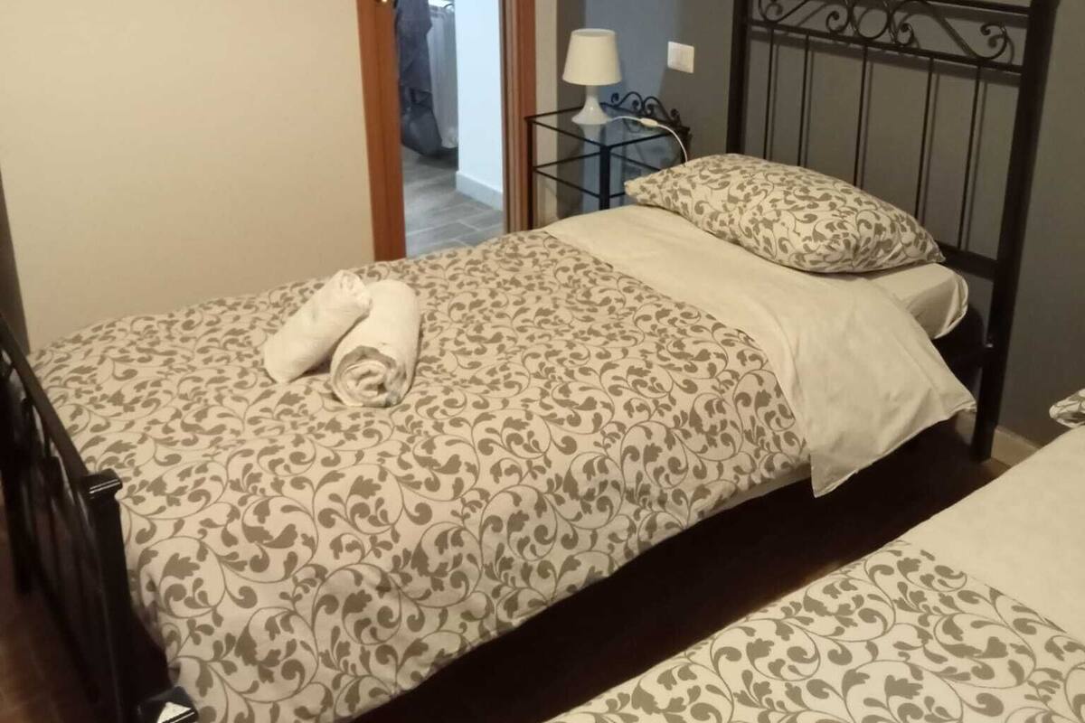 Quarto com duas camas, cada uma com roupa de cama estampada e uma mesa de cabeceira com abajur.