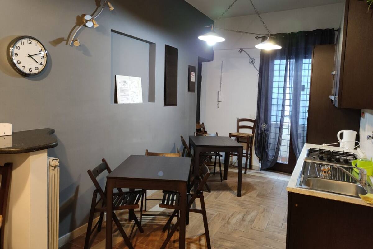 Uma cozinha com área de refeições, um relógio e uma janela com cortinas.