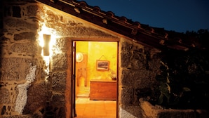 Um edifício de pedra com porta de madeira e luminária na parede.