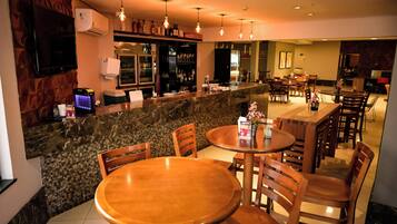 Restaurante com bancadas de mármore, cadeiras de madeira e luminárias pendentes.