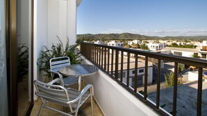 Varanda com mesa e cadeiras, vista para um horizonte urbano com edifícios e colinas.