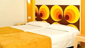 Quarto de hotel com duas camas, um grande mural na parede e uma mesinha.