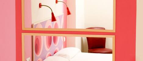 Um quarto com uma cama, uma cadeira vermelha, um espelho e uma estante.