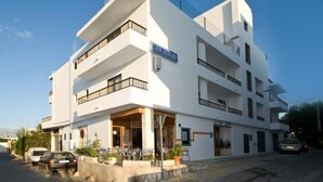Um edifício moderno branco com varandas, uma placa com a inscrição 