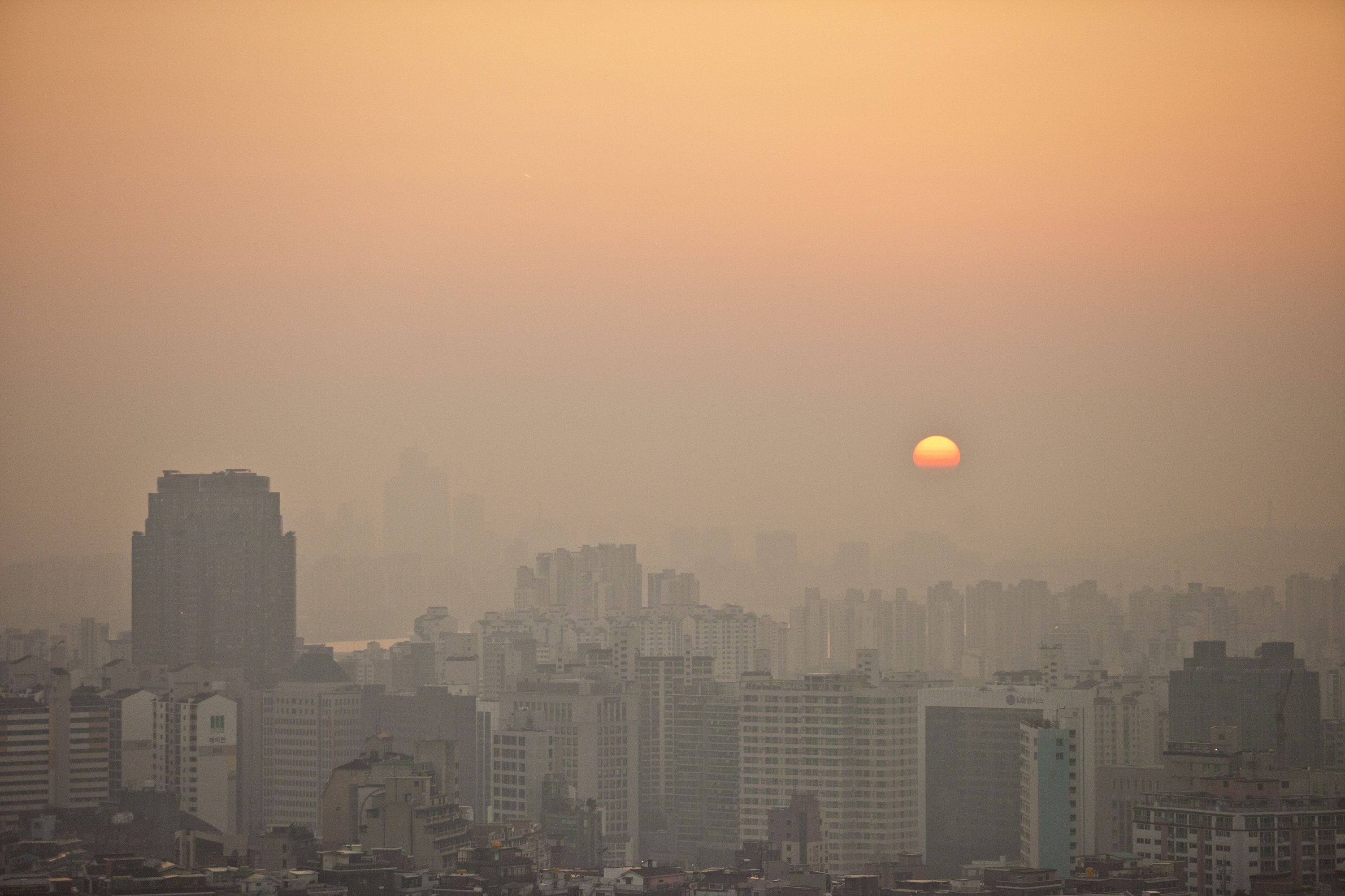 Paisagem urbana com arranha-céus e o sol se pondo.