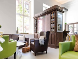 Uma sala de estar moderna com lareira, poltronas verdes, um sofá e uma mesa de centro.