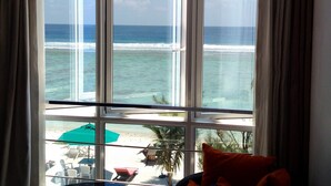 Quarto com uma grande janela com vista para uma praia e oceano.