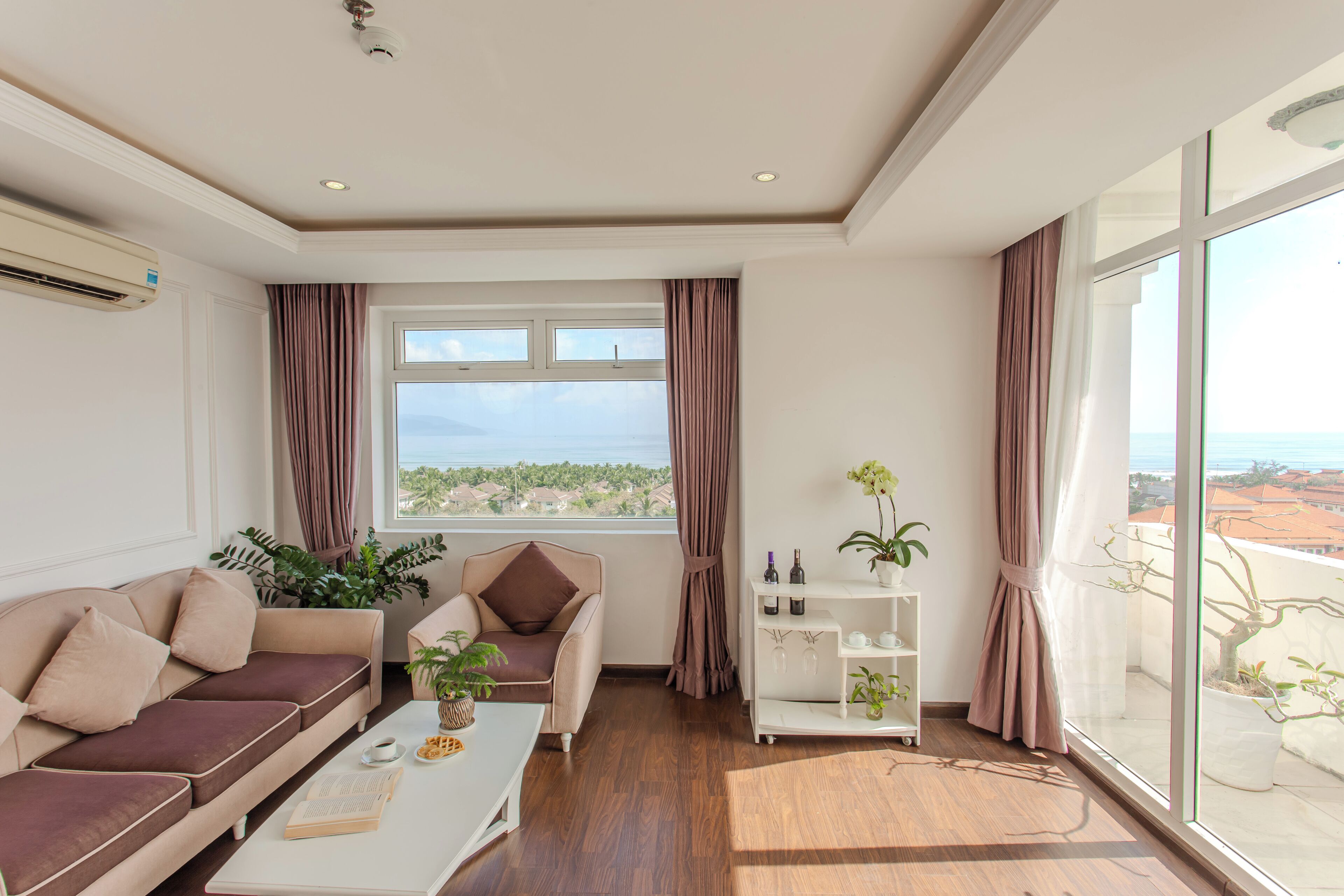 Sala de estar moderna com sofá, mesa de centro e vista da cidade através de amplas janelas.