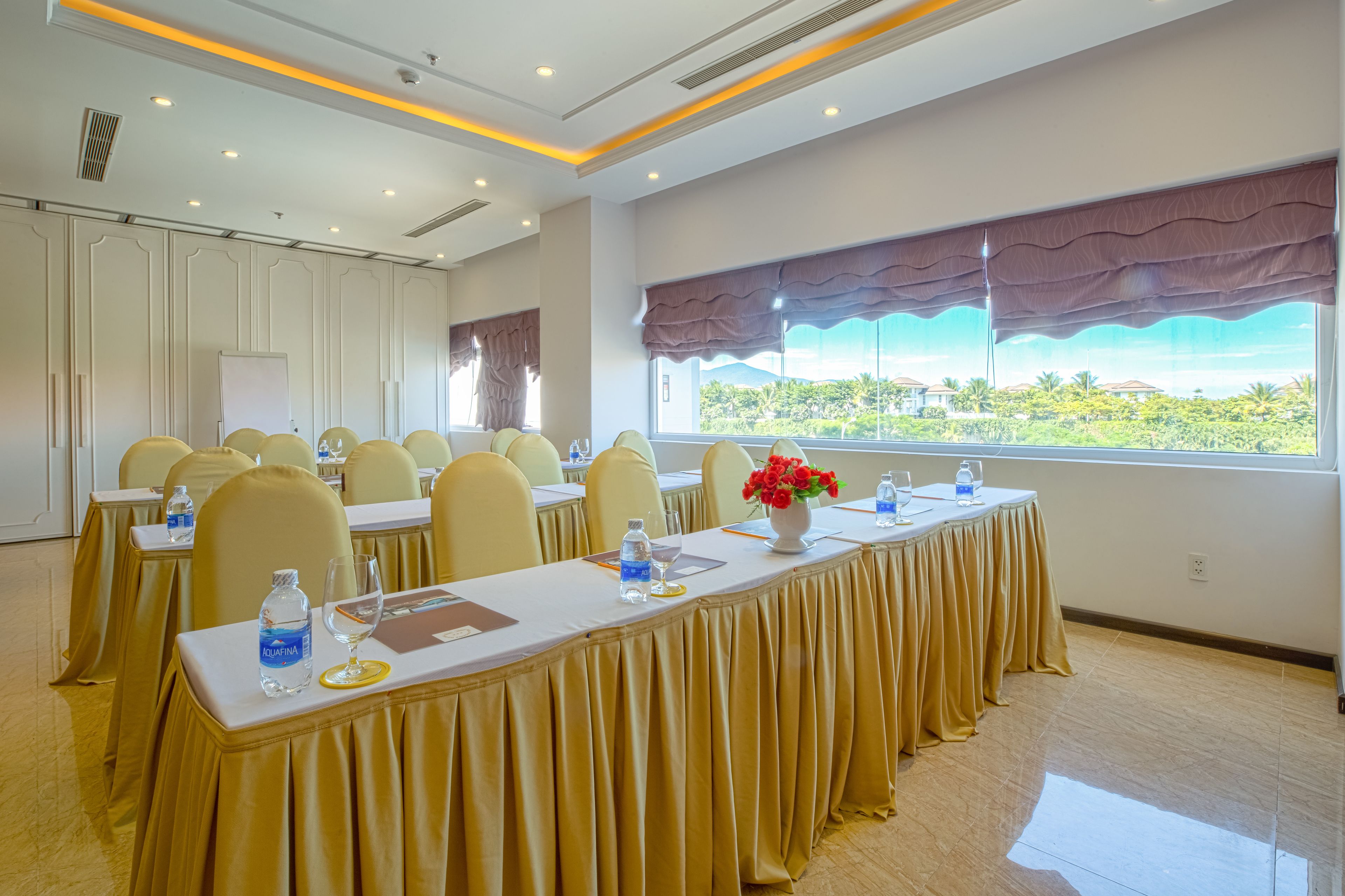 Sala de conferências com uma mesa comprida, cadeiras e vista para o verde lá fora.