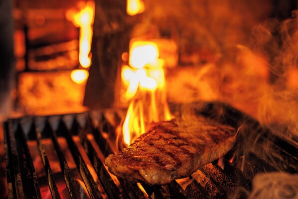 Um bife grelhando sobre chamas.