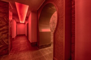 Um corredor com iluminação vermelha, parede de tijolos e chão de azulejos.