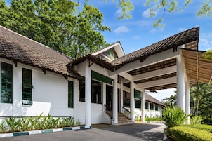Um edifício com telhado telhado, paredes brancas, molduras de janela verdes e uma galeria coberta.