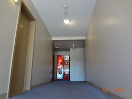 Um corredor com uma porta identificada com o número 118 e uma máquina de vendas com o logotipo da Coca-Cola.