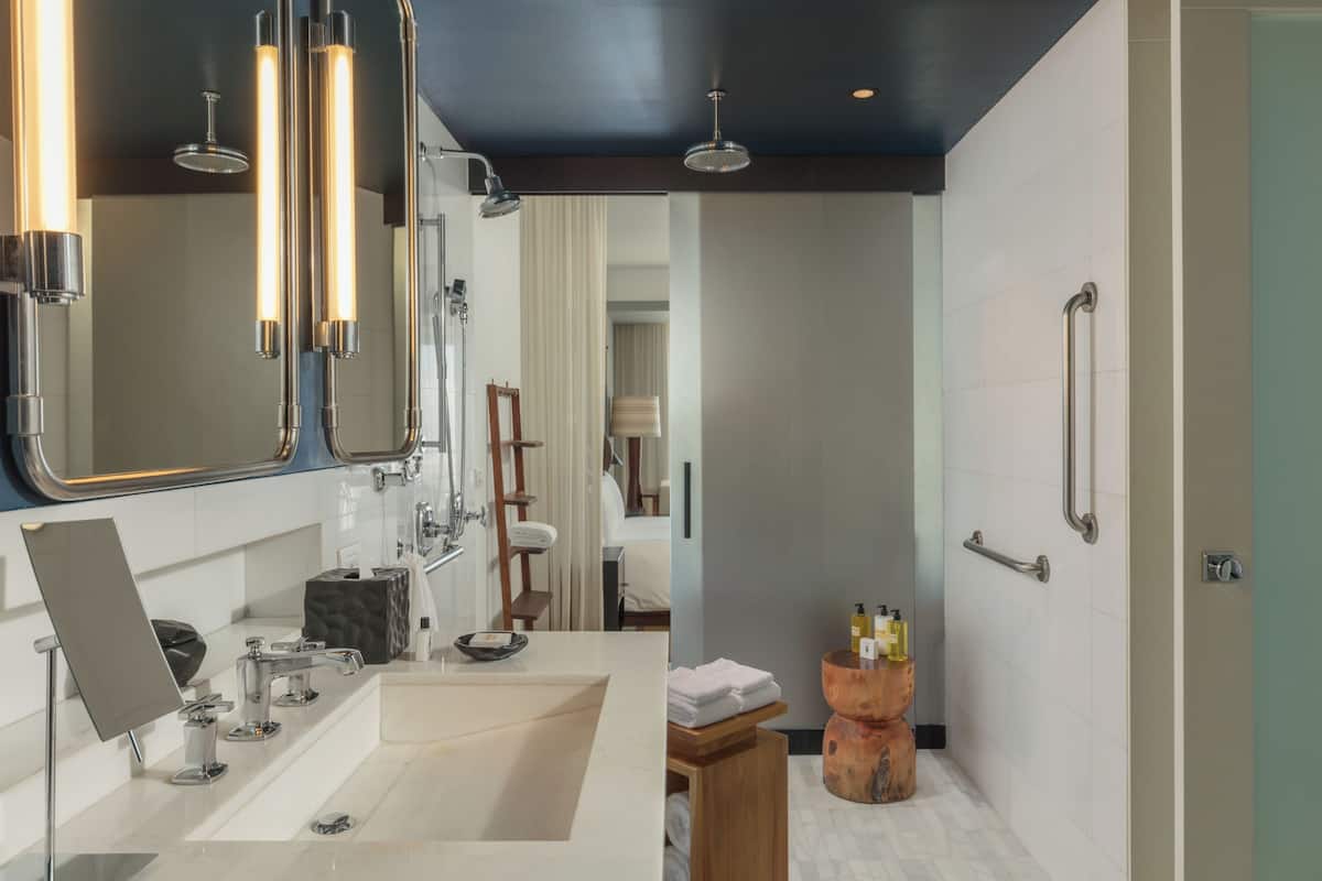 Uma casa de banho moderna com uma grande pia, vários espelhos e zona de chuveiro.