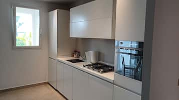 Uma cozinha moderna com armários brancos, fogão a gás e forno embutido.